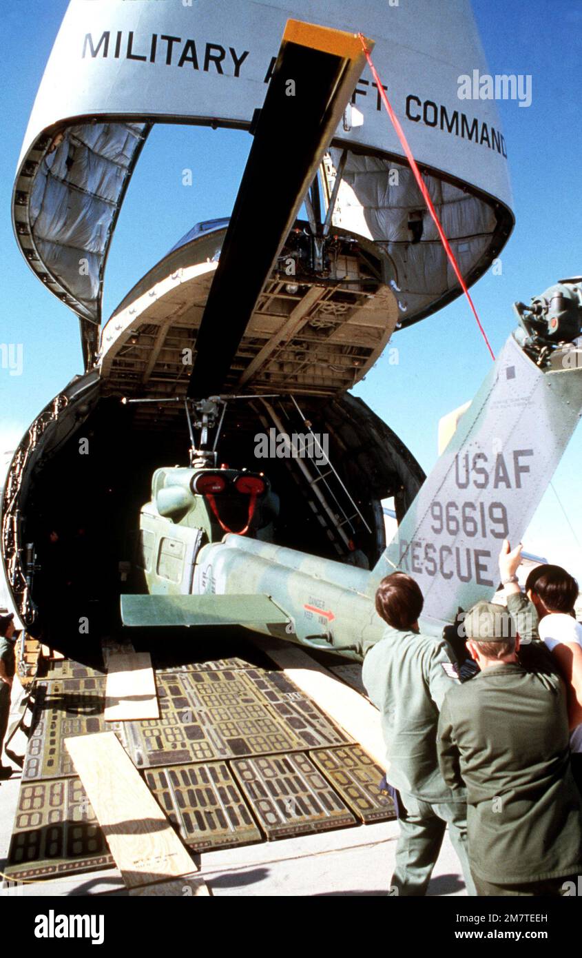 A UH-1 Iroquois helicopter is being unloaded from a C-5A Galaxy ...