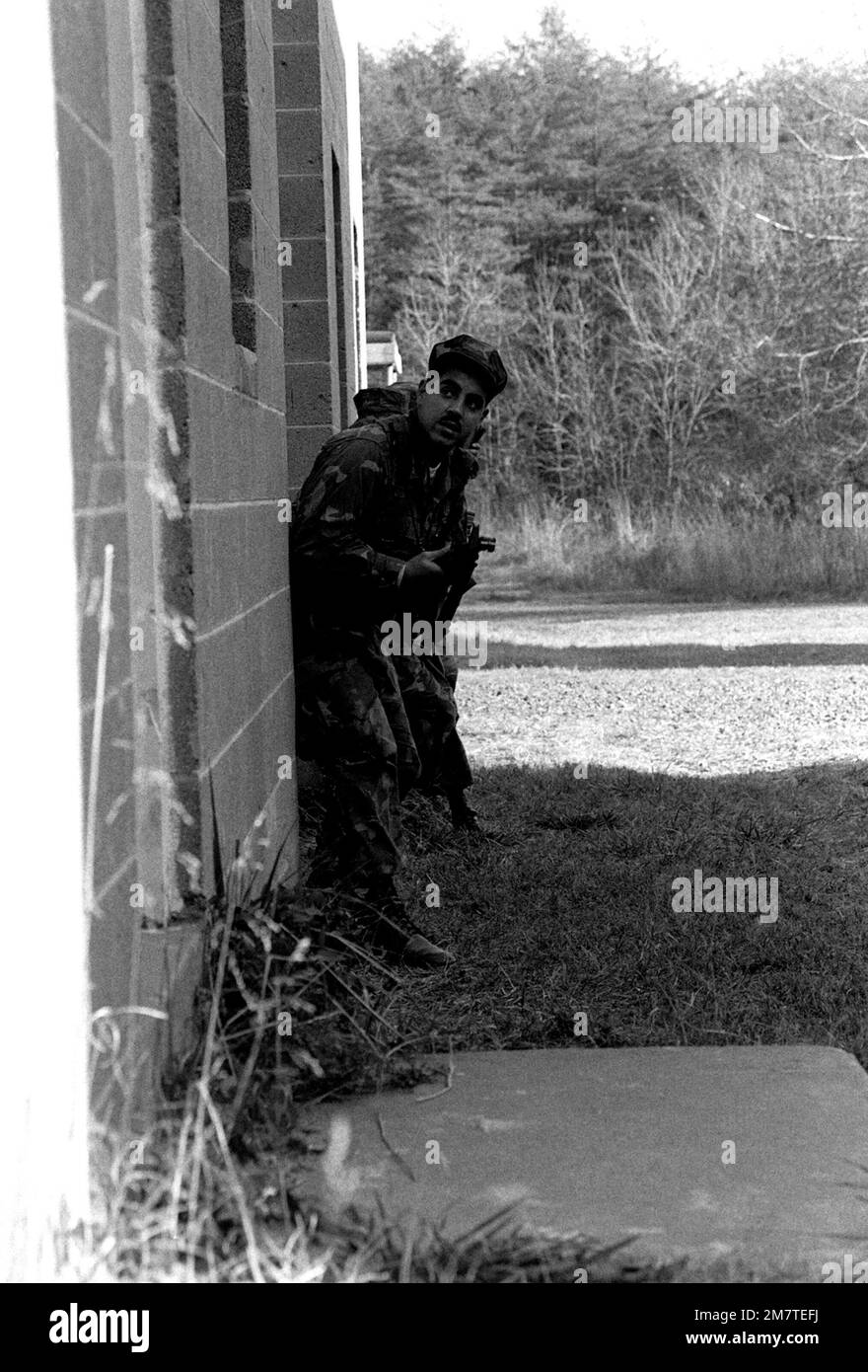 A military policeman looks around the corner of a building during a ...