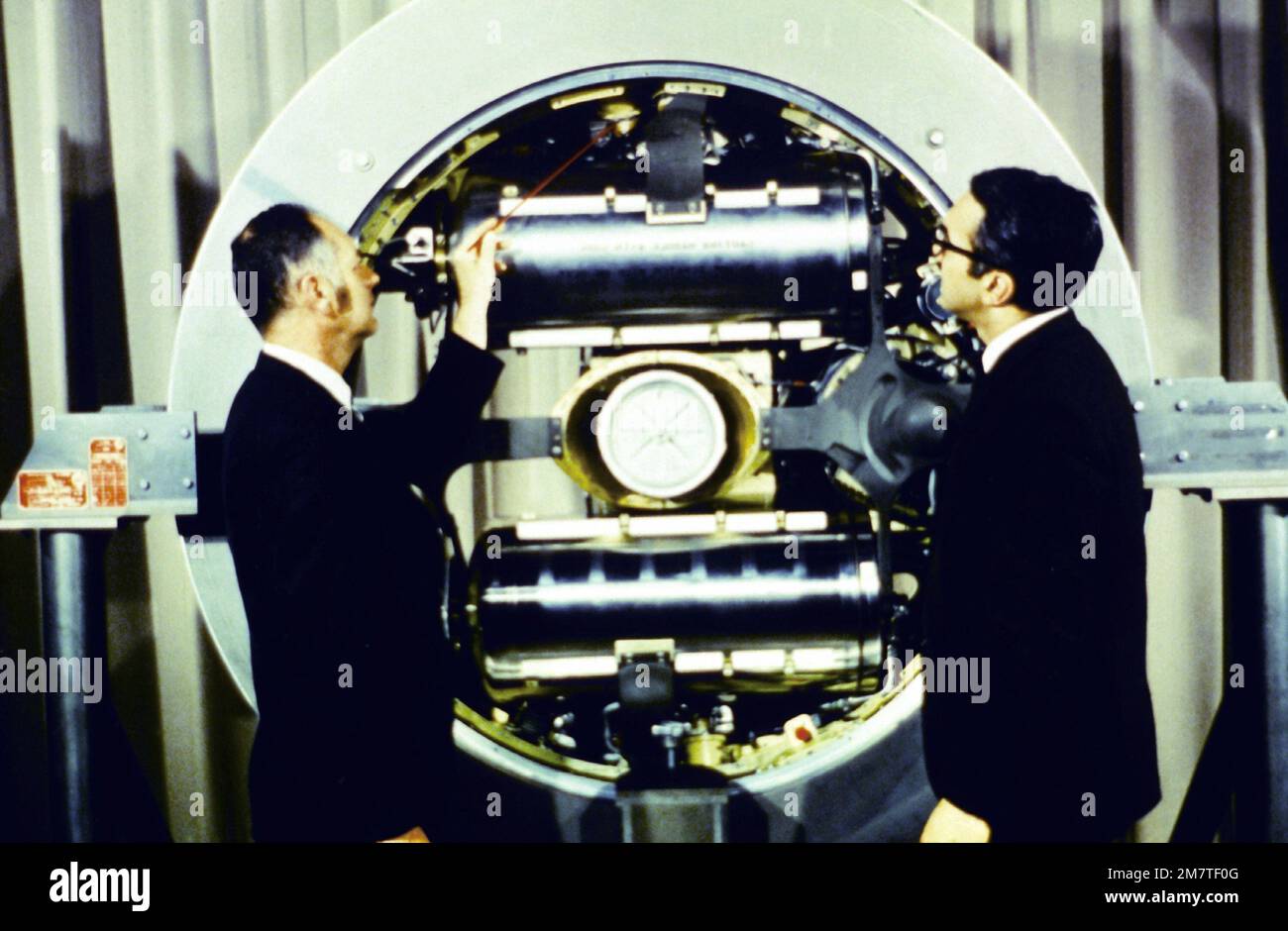 Two civilian technicians look at the underneath side of a Minuteman ...