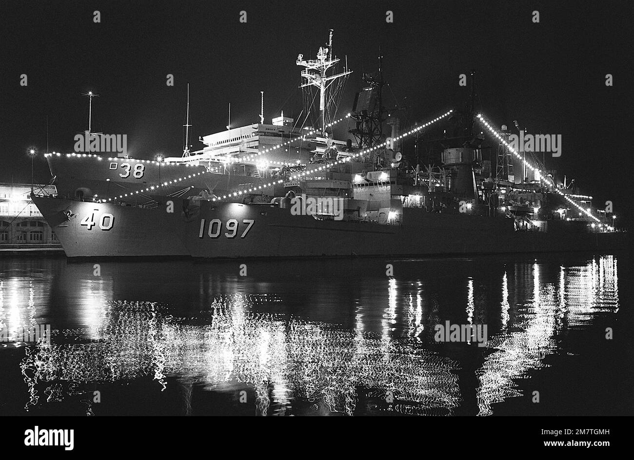 Port view of three U.S. ships, with lights strung up in the rigging, in ...
