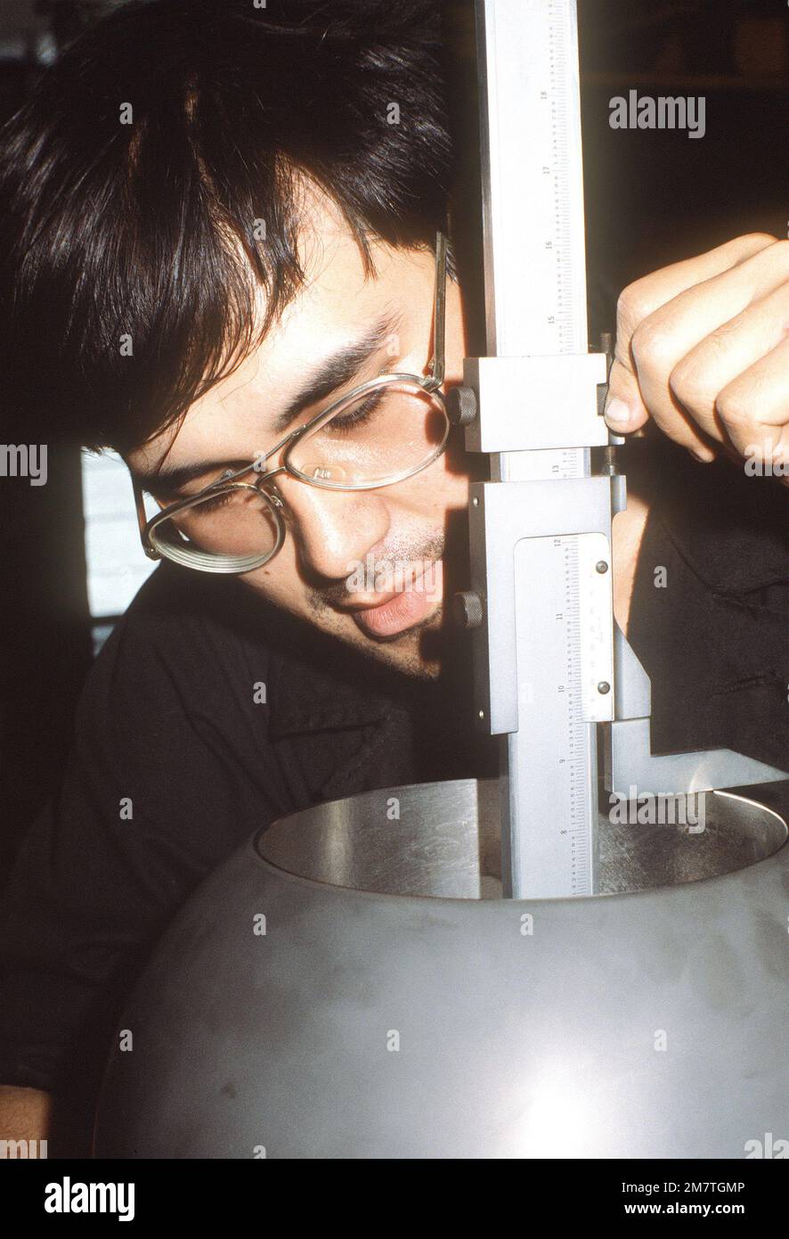 Machinist's Mate 2nd Class (MM2) Joseph Leone works on equipment in the ...