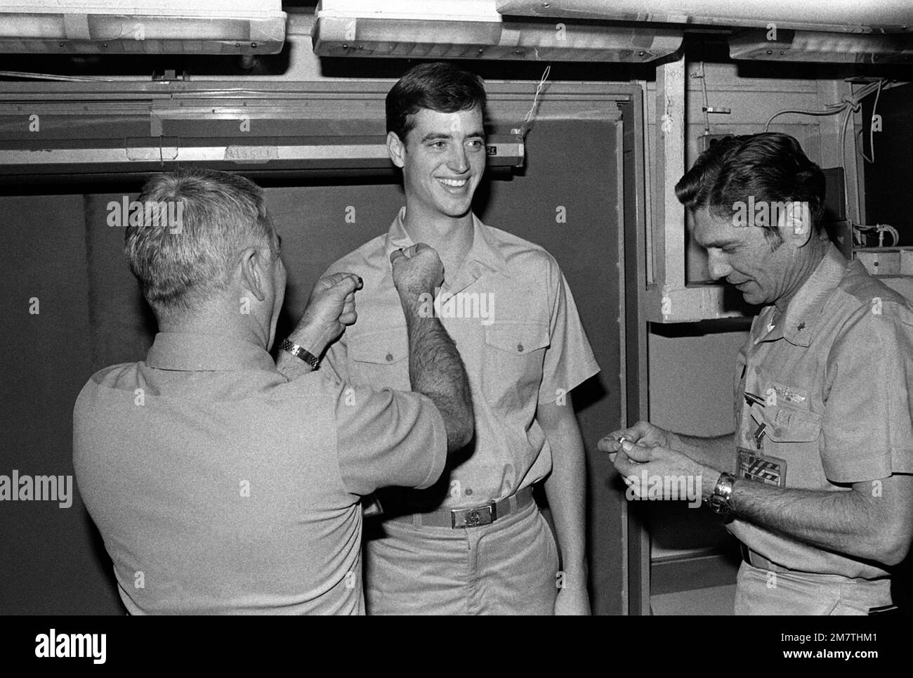 ENSIGN R. Hill, center, is frocked to Lieutenant Junior grade by ...
