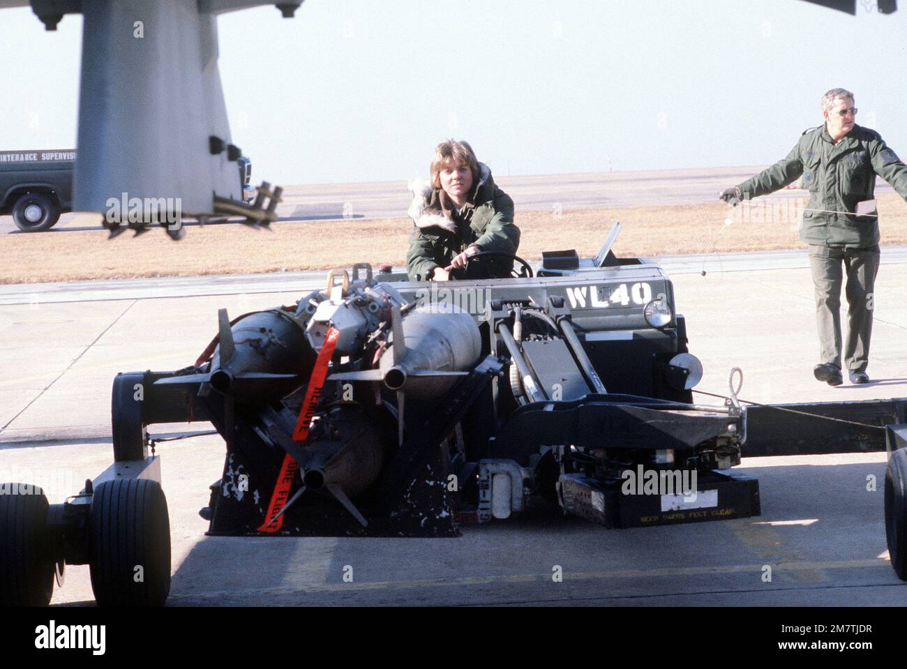 Ground crewmen move a bomb loader toward an F-16 Fighting Falcon ...