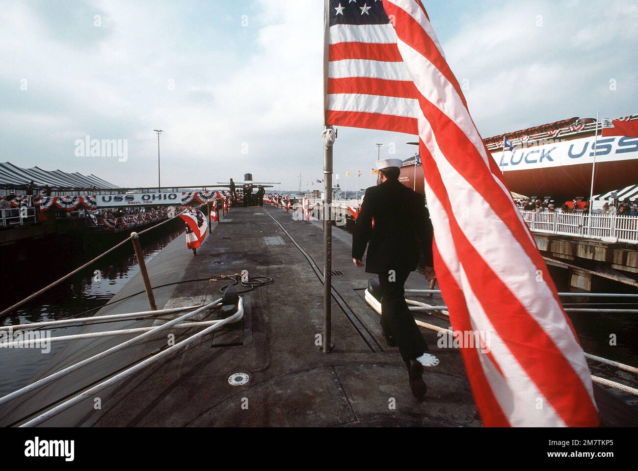 A crewman walks by the US flag on the deck of the nuclear-powered ...