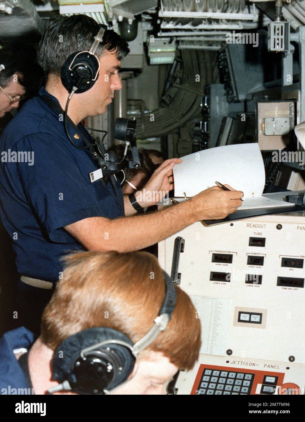 LCDR Larry Mayes, blue crew weapons officer, makes entries in a ...