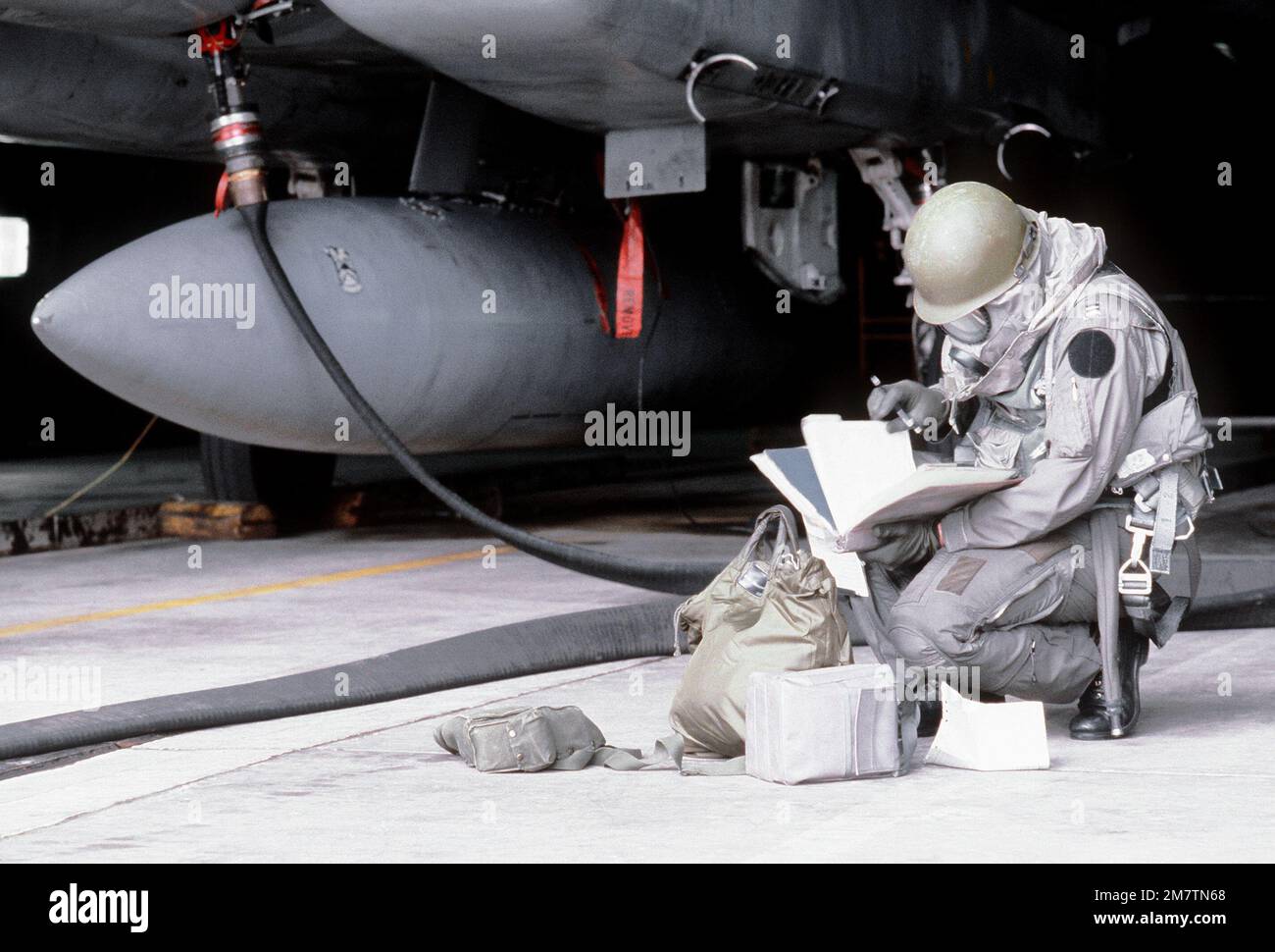 AN F-15 Eagle aircraft pilot, in protective chemical warfare gear, logs ...