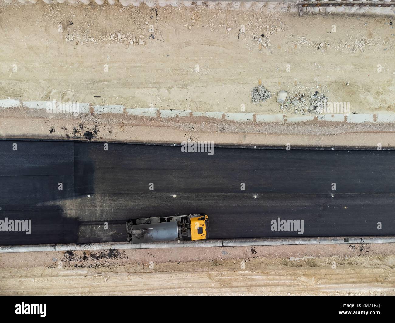 yellow truck pouring bitumen over a new road. Aerial drone shot. Road ...