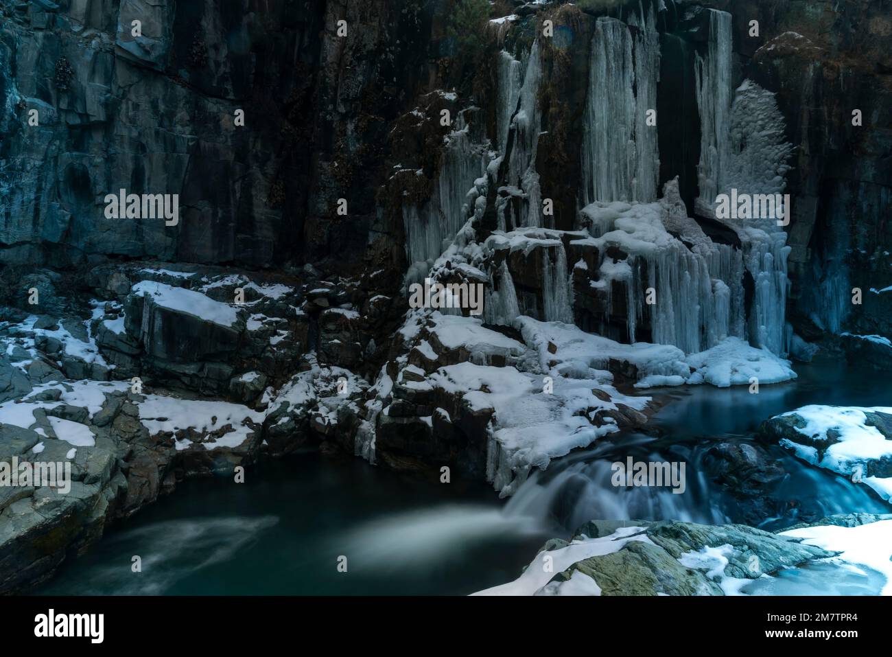 A long exposure shot of frozen Aharbal waterfall during a cold cloudy ...