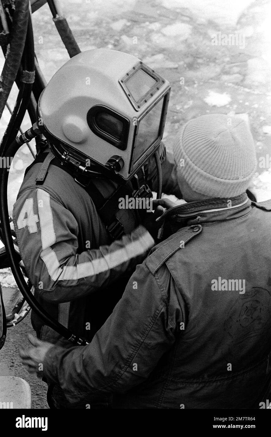 A Navy diver wearing Mark 12 dive gear prepares to enter the icy water ...