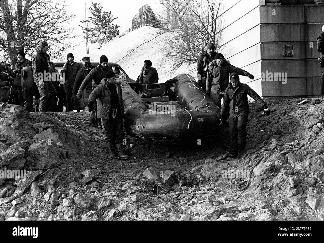 Navy divers carry a rubber raft down to the river bank for use in the ...