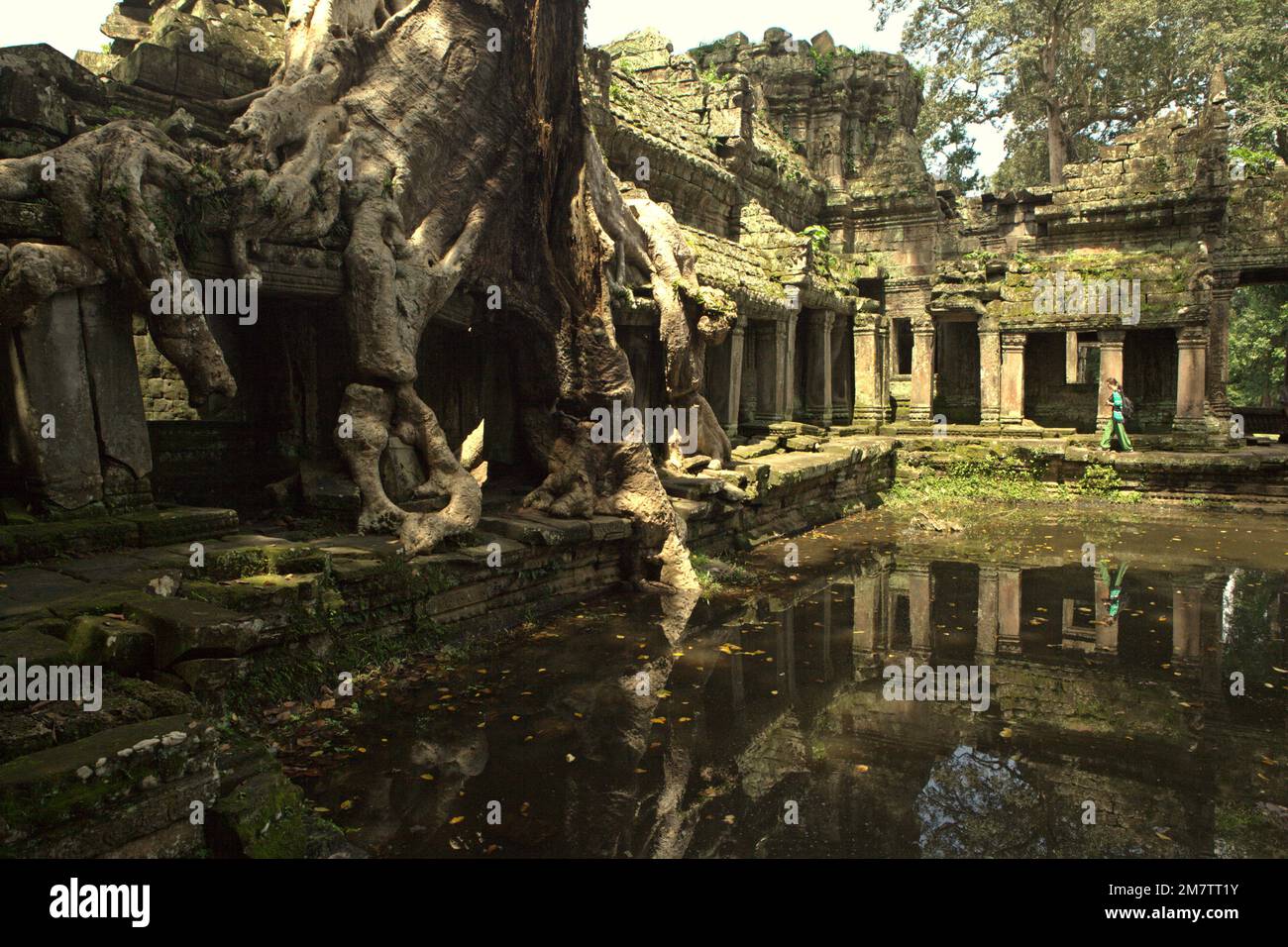A woman visitor walking on a walkway between an ancient man-made pond ...