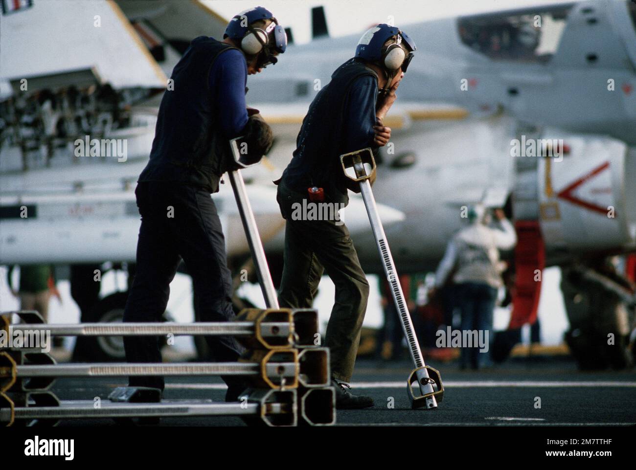 Two flight deck crewmen prepare to use chocks to secure aircraft aboard ...