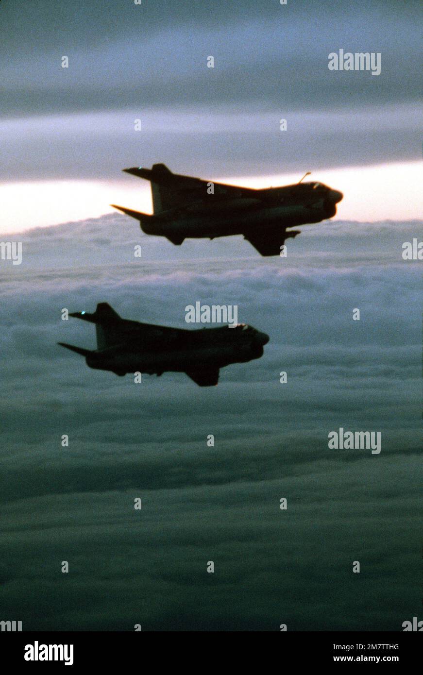 A silhouetted air-to-air right side view of two A-7 Corsair aircraft ...