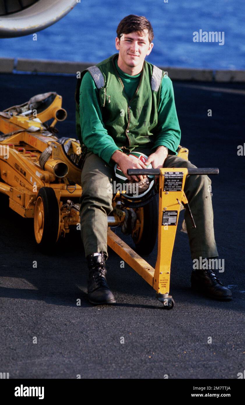 A flight deck crewman sits on a bomb loader aboard the aircraft carrier ...