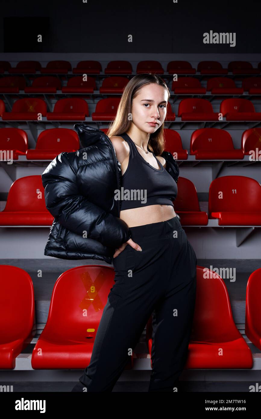 Young attractive girl wearing puffer jacket standing against tiers of ...