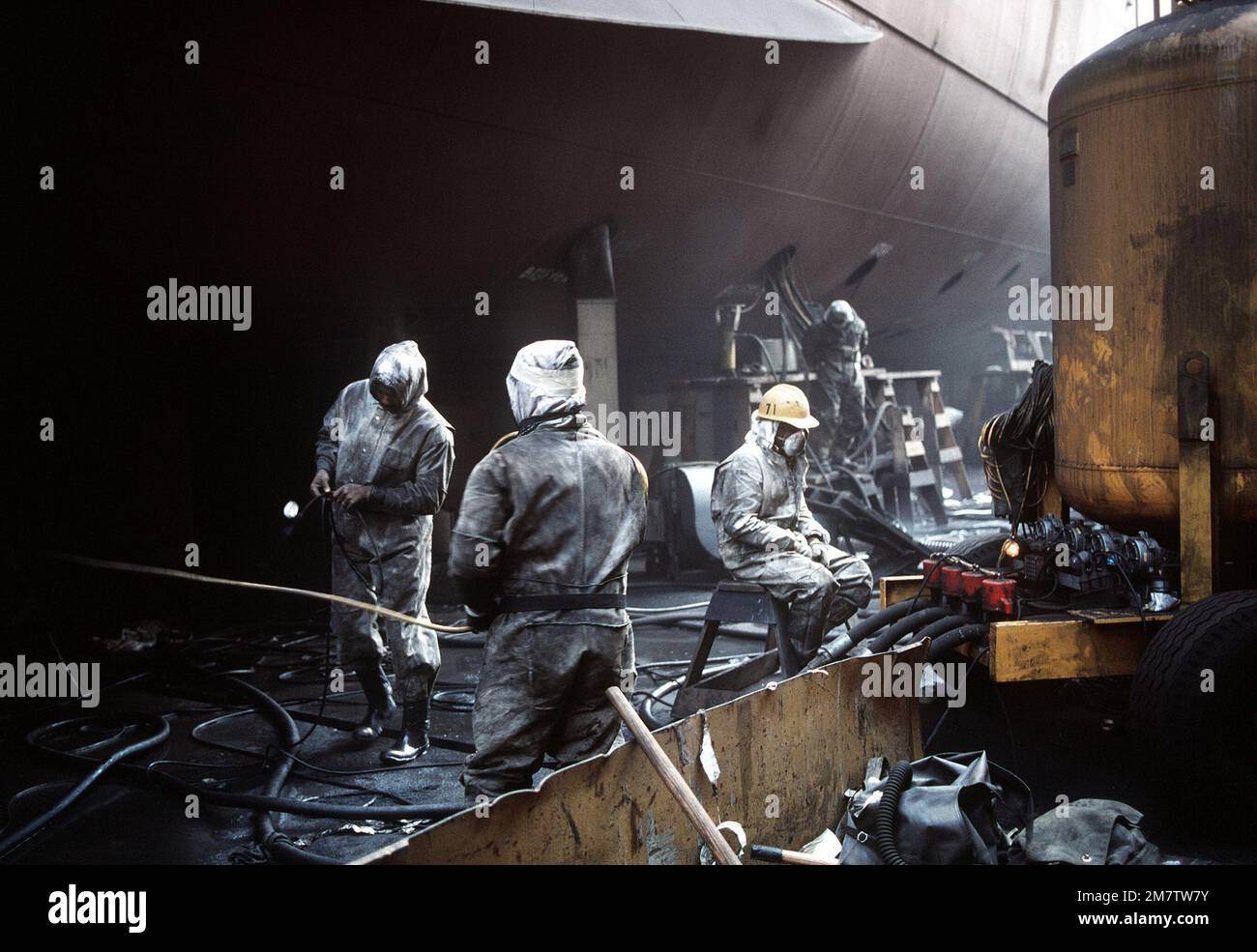 Shipyard personnel wear protective gear as they work on the hull of the ...