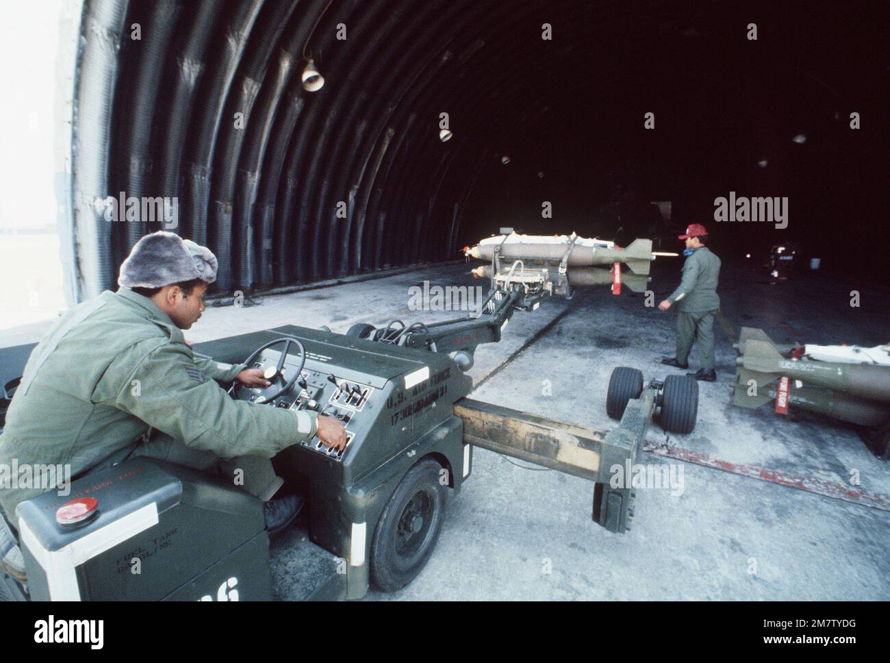 SGT Donnie McGabe operates a bomb loader, as A1C Daniel Franquez gives ...