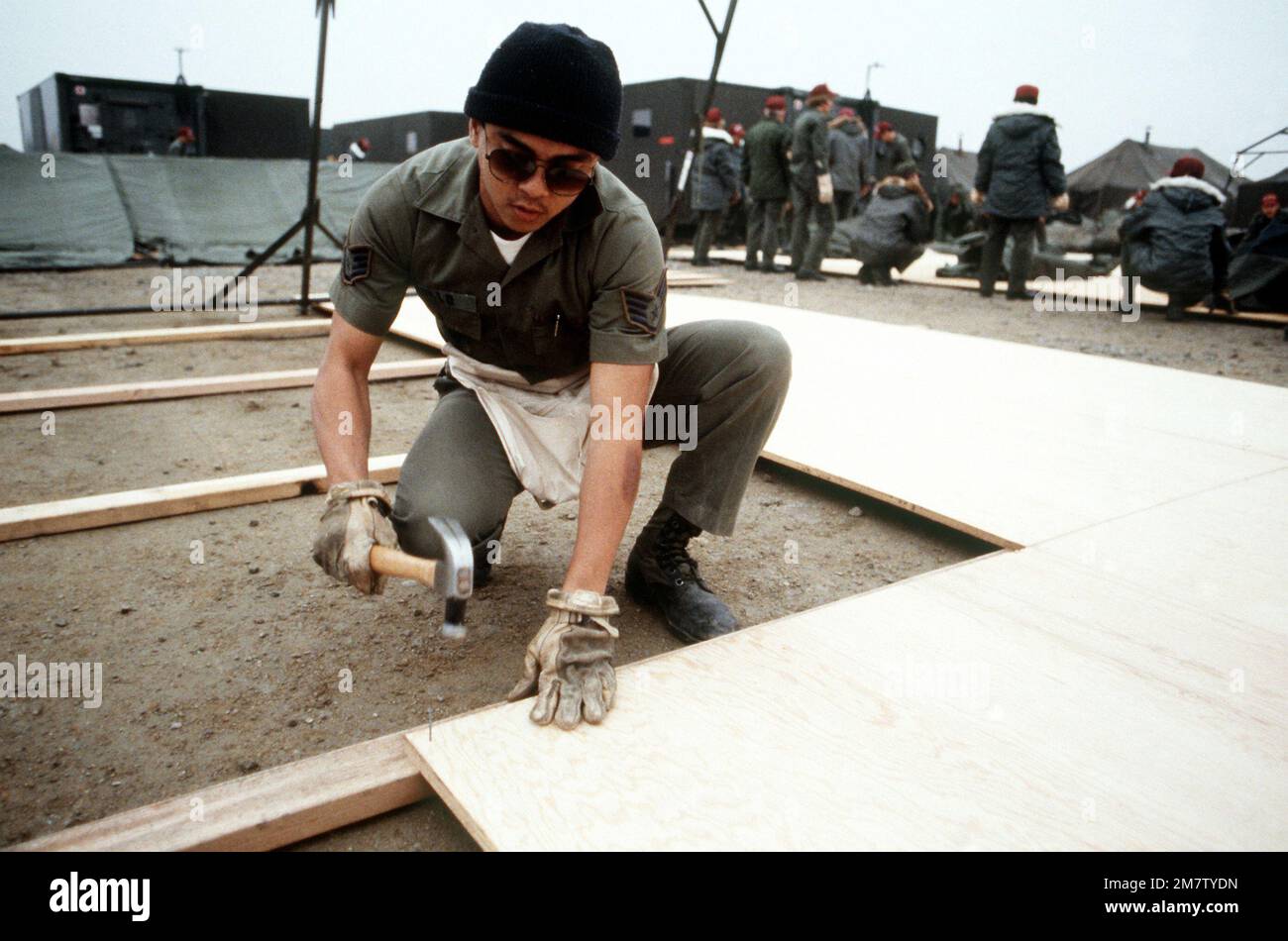A staff sergeant lays the floor for a tent being erected for the 656th ...