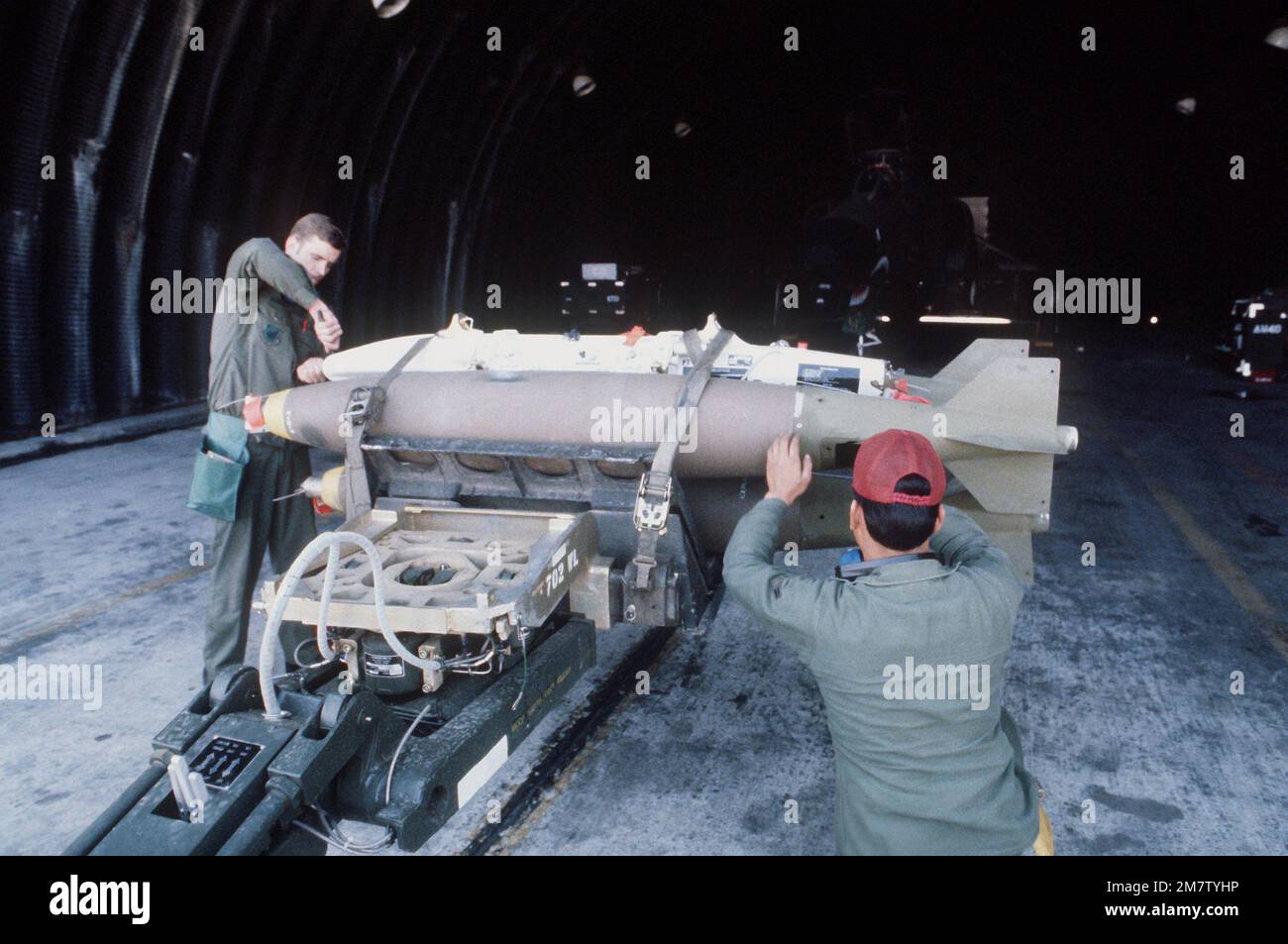Live ordnance is prepared for loading aboard an F-4 Phantom II aircraft ...
