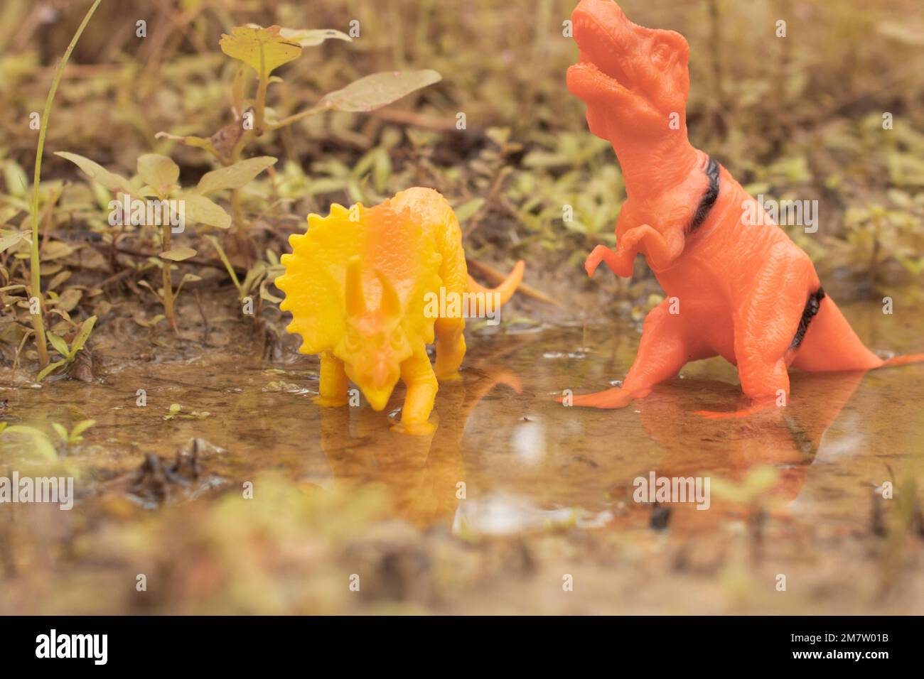 dinosaur toys illustrating loitering around the lake Stock Photo - Alamy