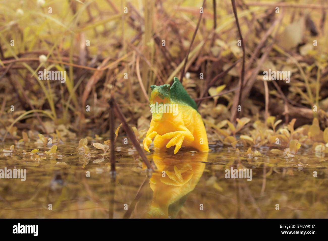 dinosaur toys illustrating loitering around the lake Stock Photo - Alamy