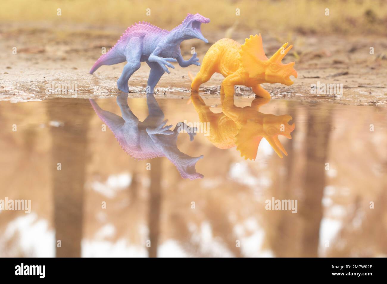 dinosaur toys illustrating loitering around the lake Stock Photo - Alamy
