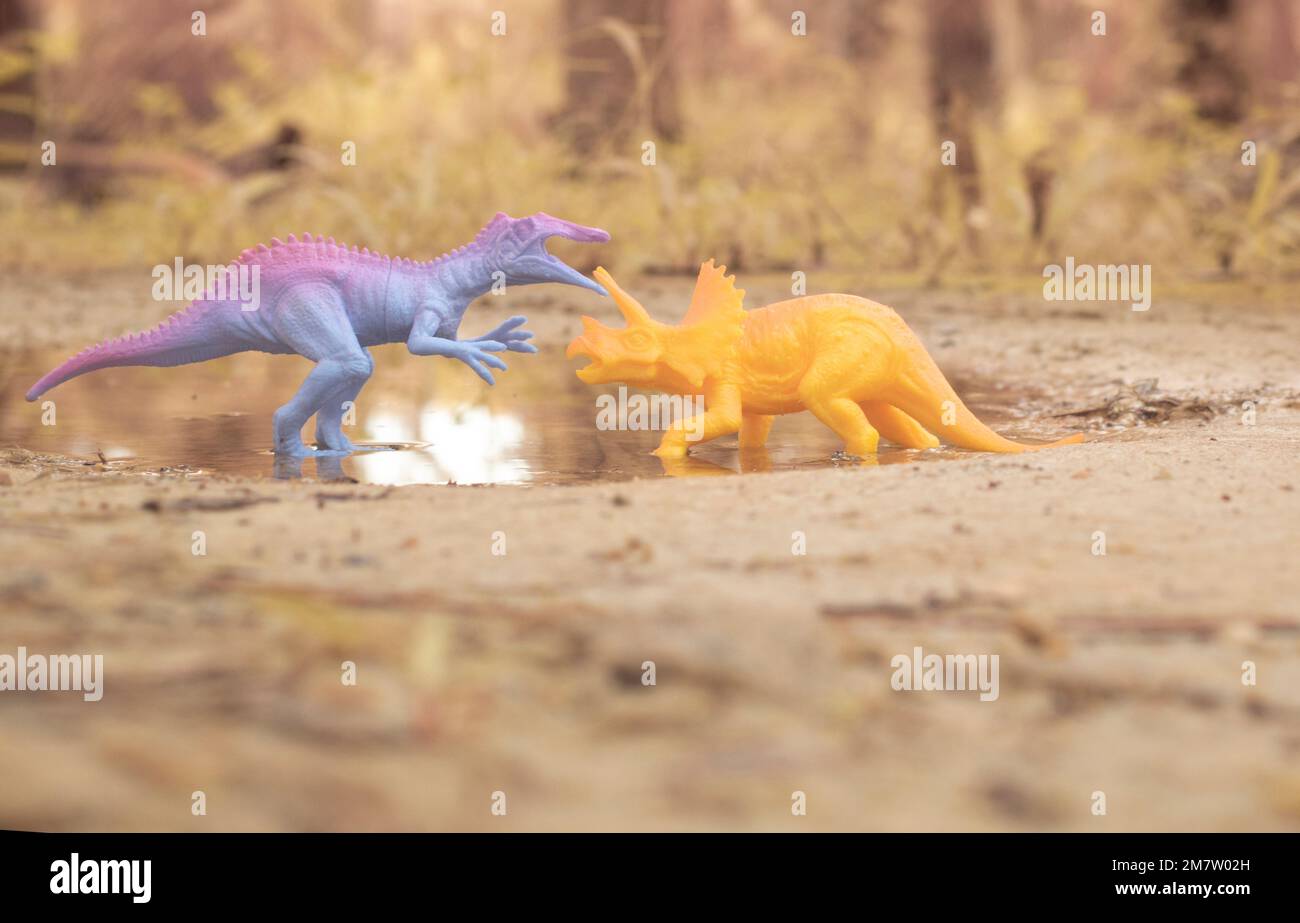 dinosaur toys illustrating loitering around the lake Stock Photo - Alamy