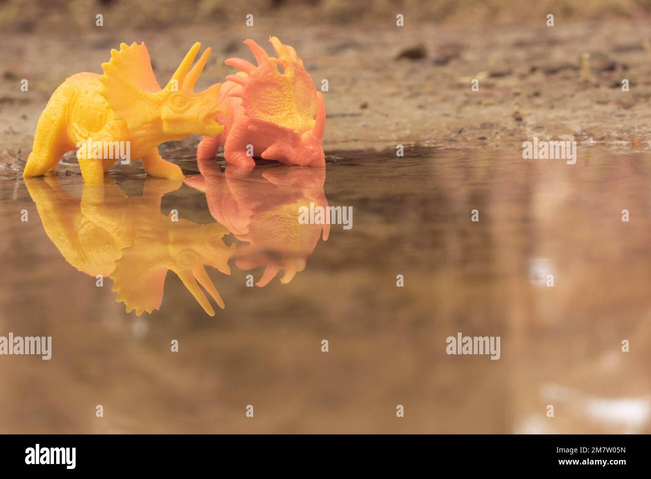 dinosaur toys illustrating loitering around the lake Stock Photo - Alamy