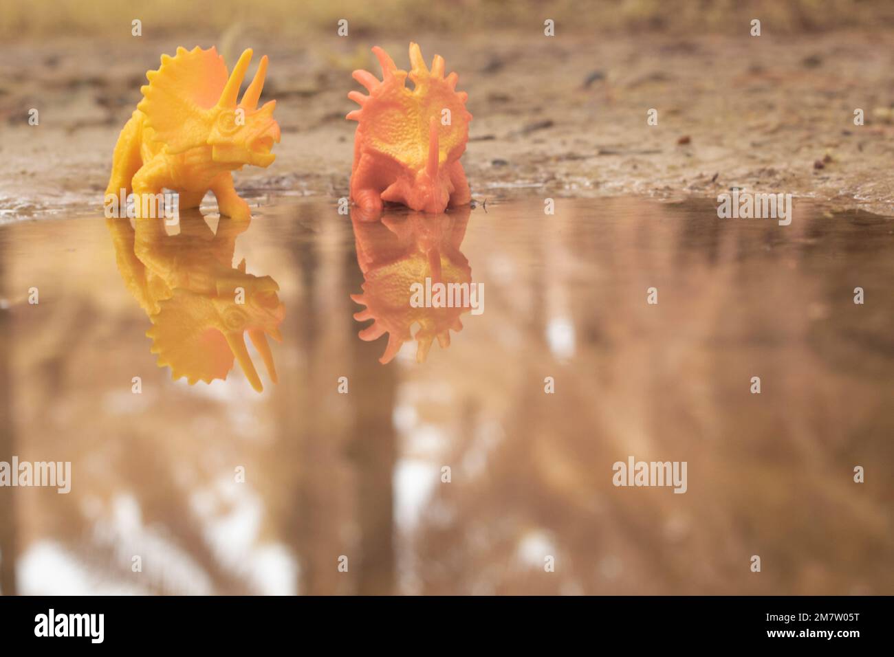 dinosaur toys illustrating loitering around the lake Stock Photo - Alamy