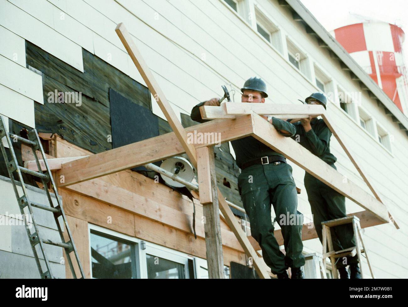 Seabees from Construction Battalion 416 construct a porch roof on a ...