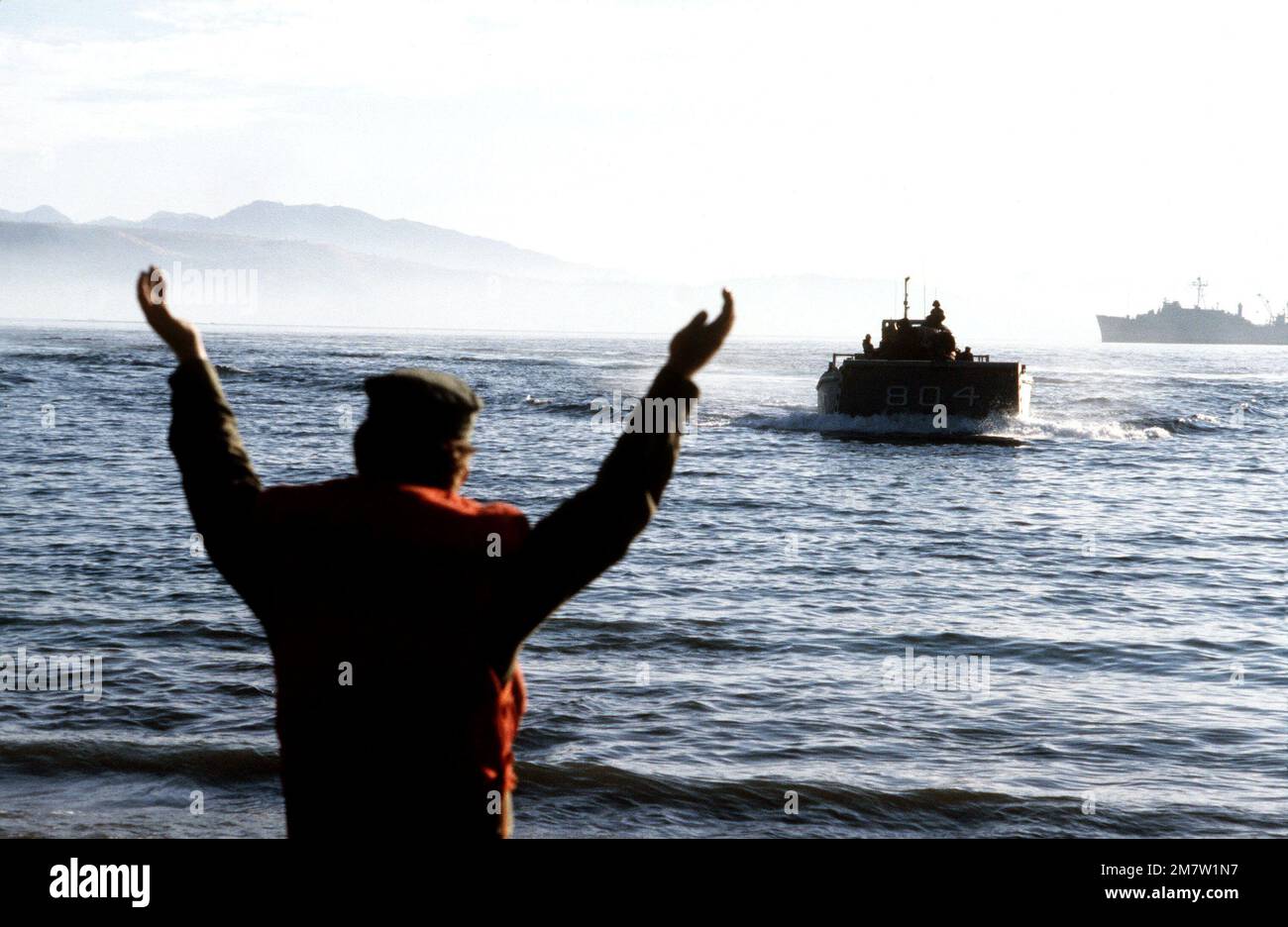 A Navy beachmaster directs a mechanized landing craft (LCM 804) onto ...