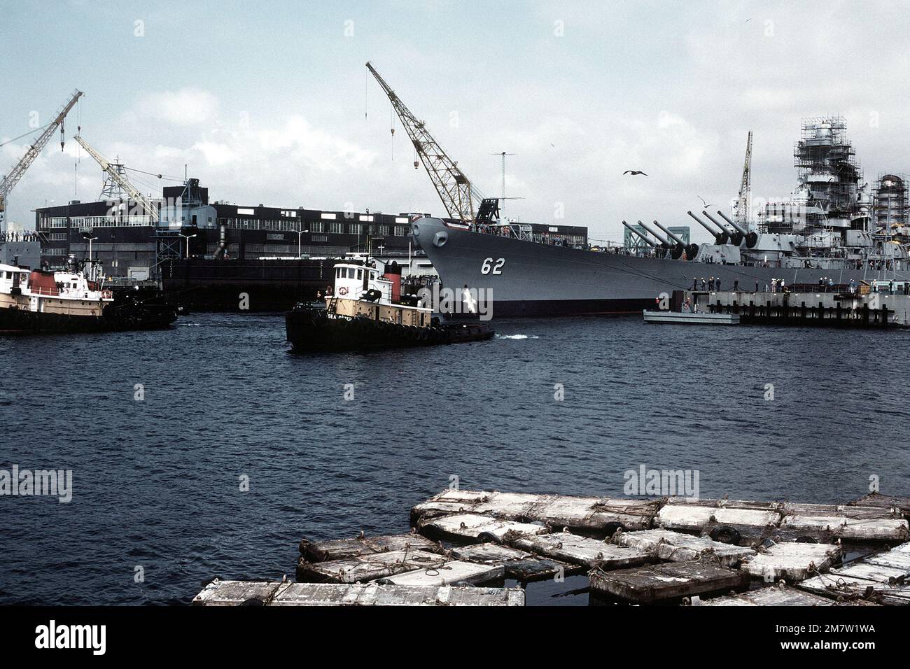 Tugs and barges pull the battleship NEW JERSEY (BB-62) out of drydock ...