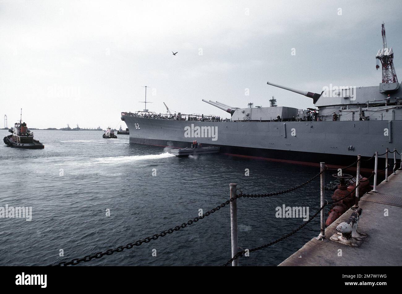 Tugs and barges pull the battleship NEW JERSEY (BB-62) out of drydock ...
