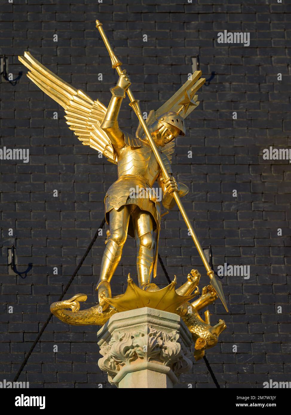 A golden angel statue killing the evil dragon with a spear, daylight ...