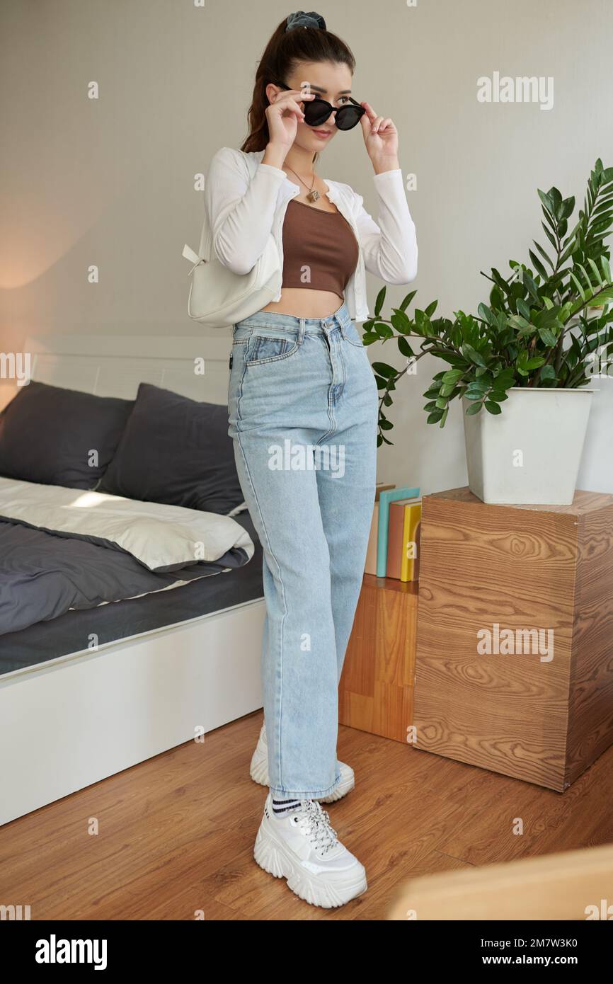 Young woman putting on sunglasses when leaving house to hang out with ...