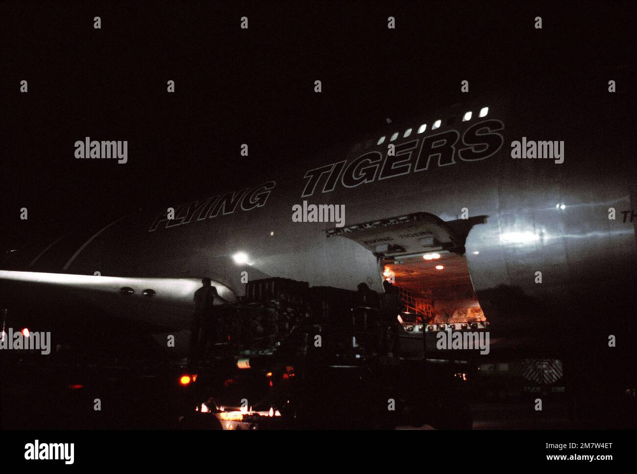 Cargo is loaded aboard a 747 Flying Tiger aircraft at night during ...