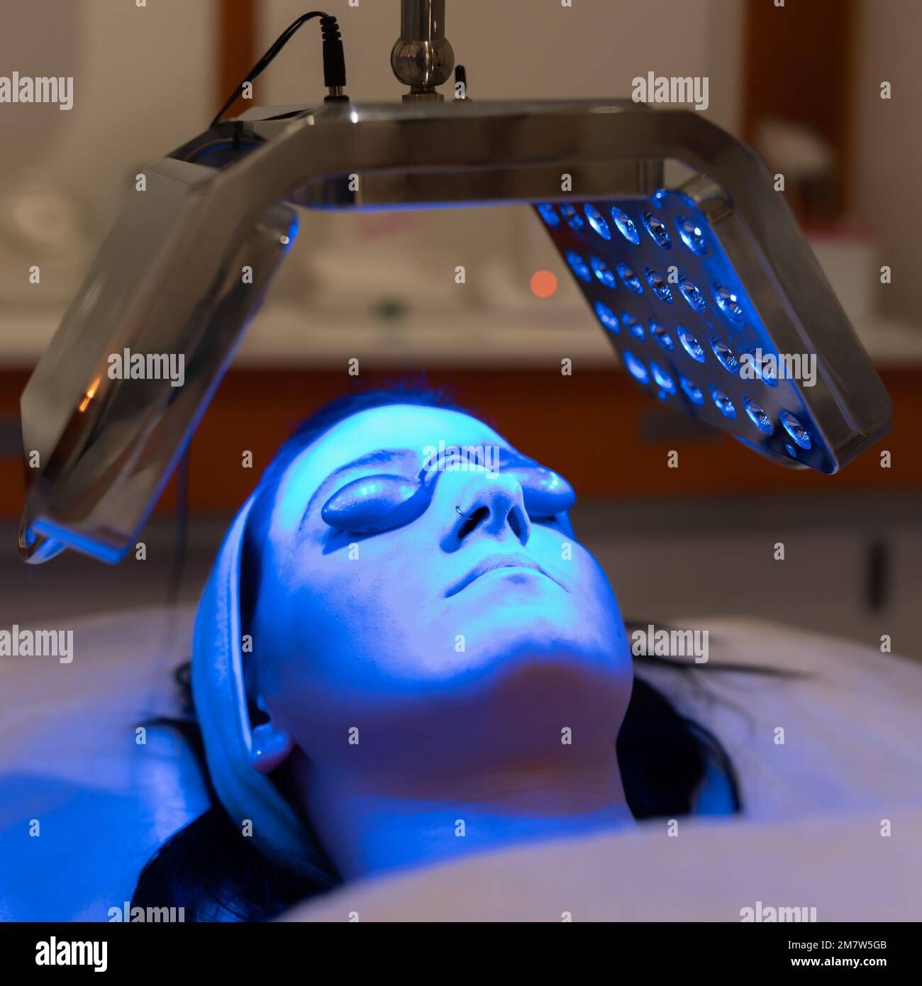 Young woman having blue LED light facial therapy treatment in beauty ...