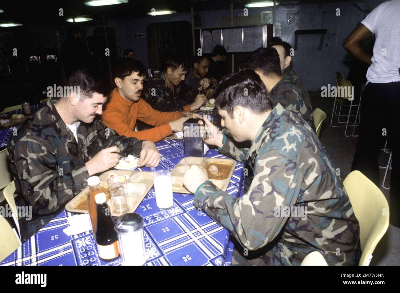 Marines eat dinner in the dining area aboard the amphibious assault ...