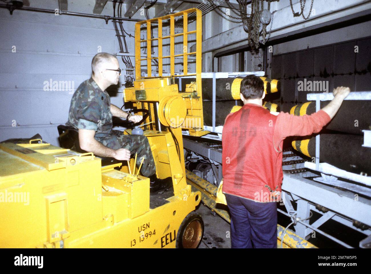 A fork lift is used to move bomb racks to a storage area aboard the ...