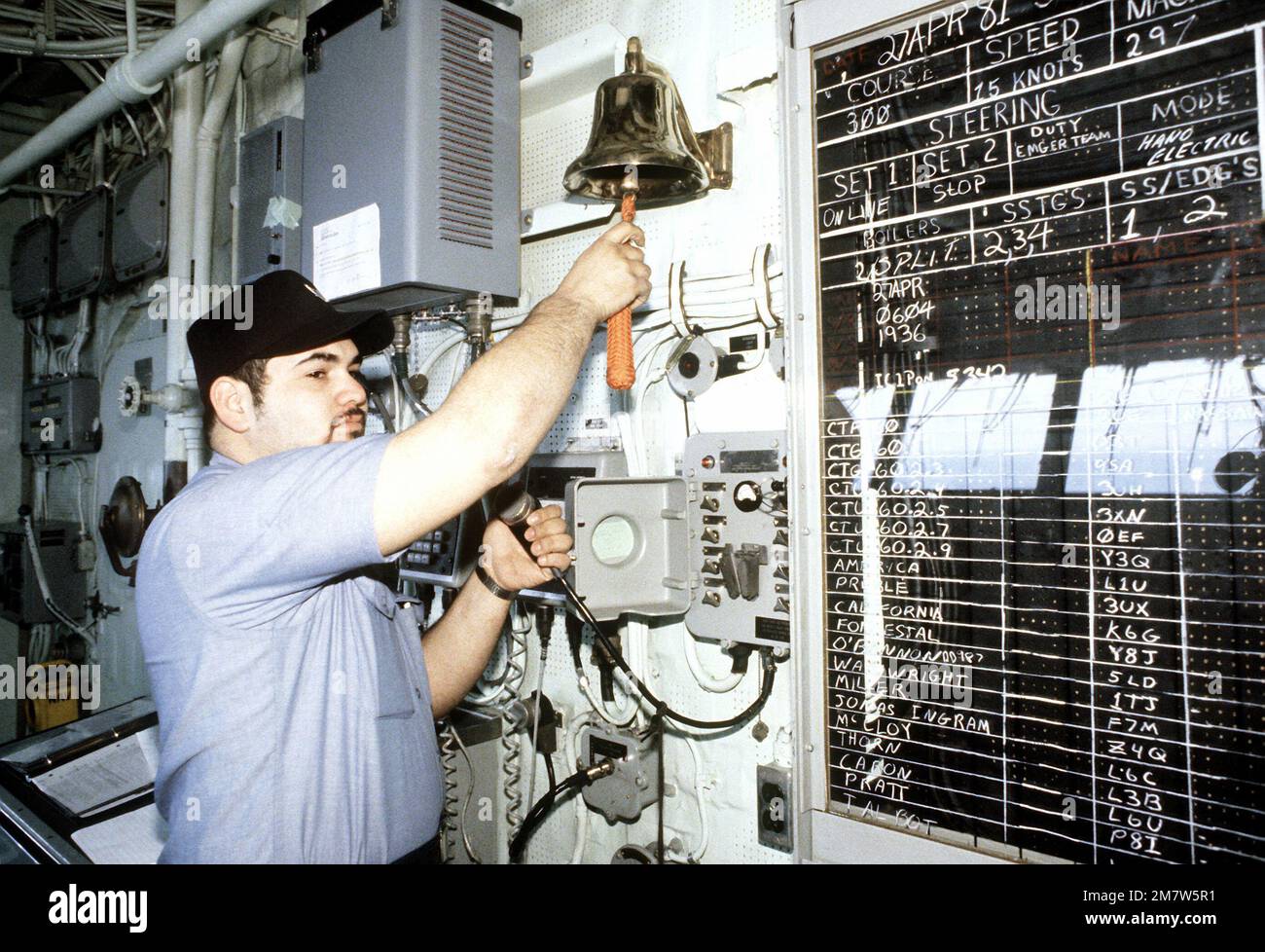 A crewman rings a bell prior to making an announcement to the ship's ...