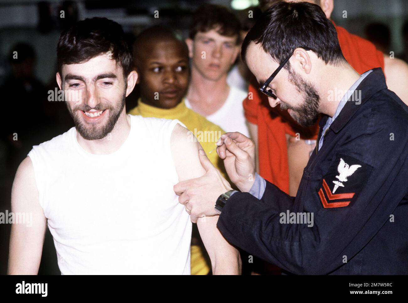 A Navy corpsman prepares a crewman for an inoculation aboard the ...