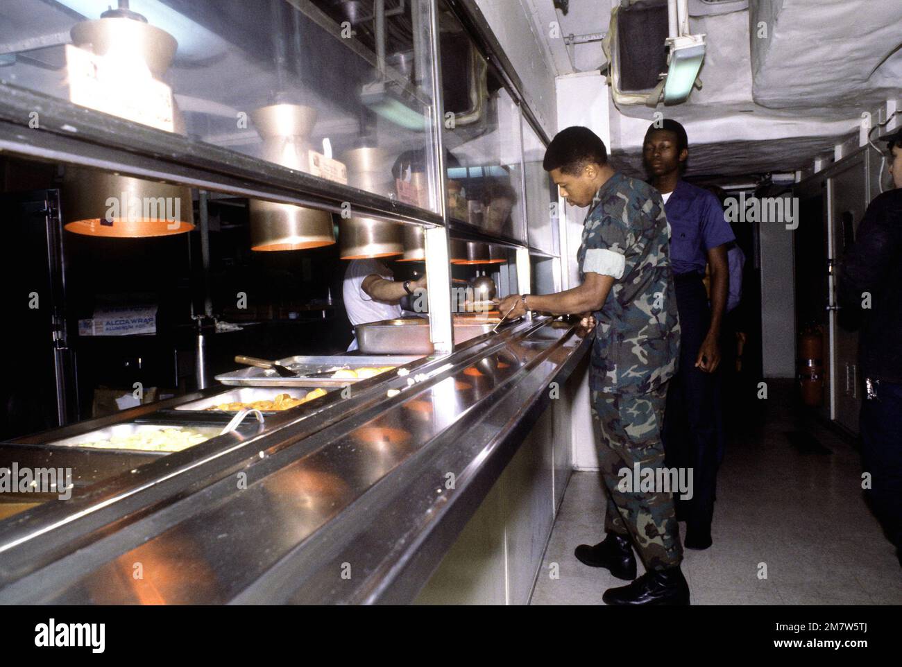 Marines proceed through the food service line in the dining area aboard ...