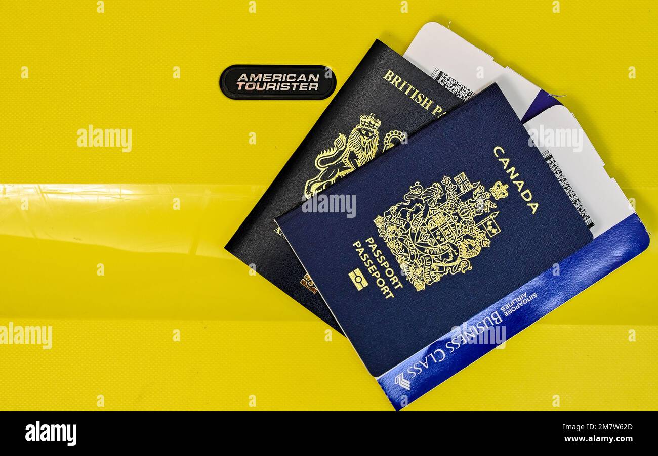 Passports with Business Class ticket, yellow luggage as background ...