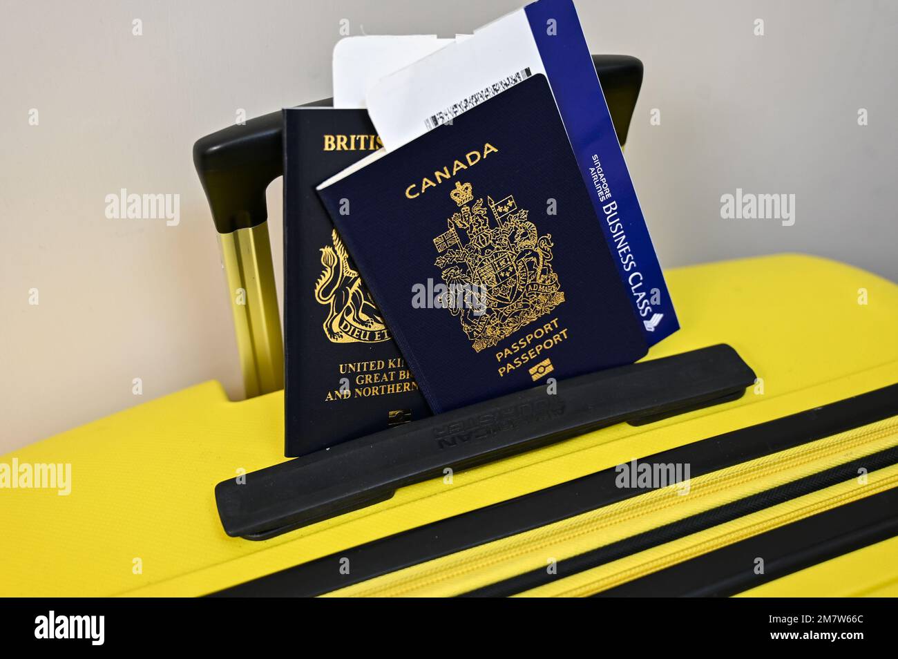 Passports with Business Class ticket, yellow luggage as background ...