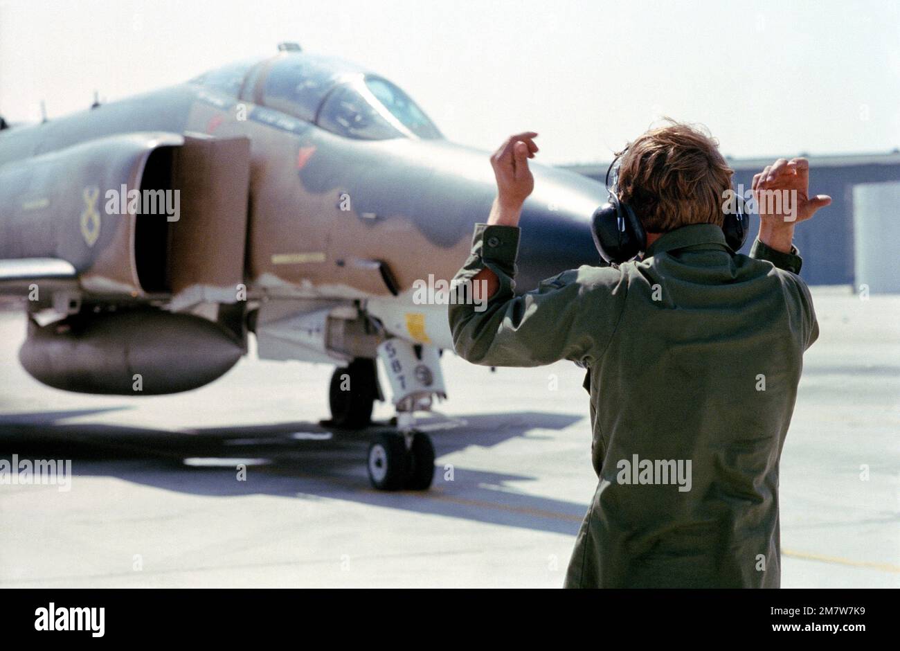 A ground crewman from the 37th Tactical Fighter Wing guides an F-4 ...
