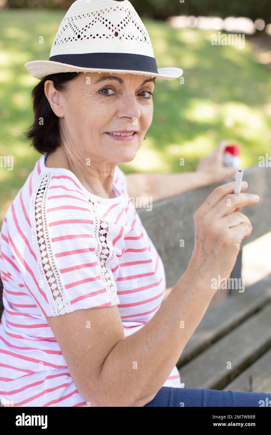 older woman sitting on bench and smoking Stock Photo - Alamy