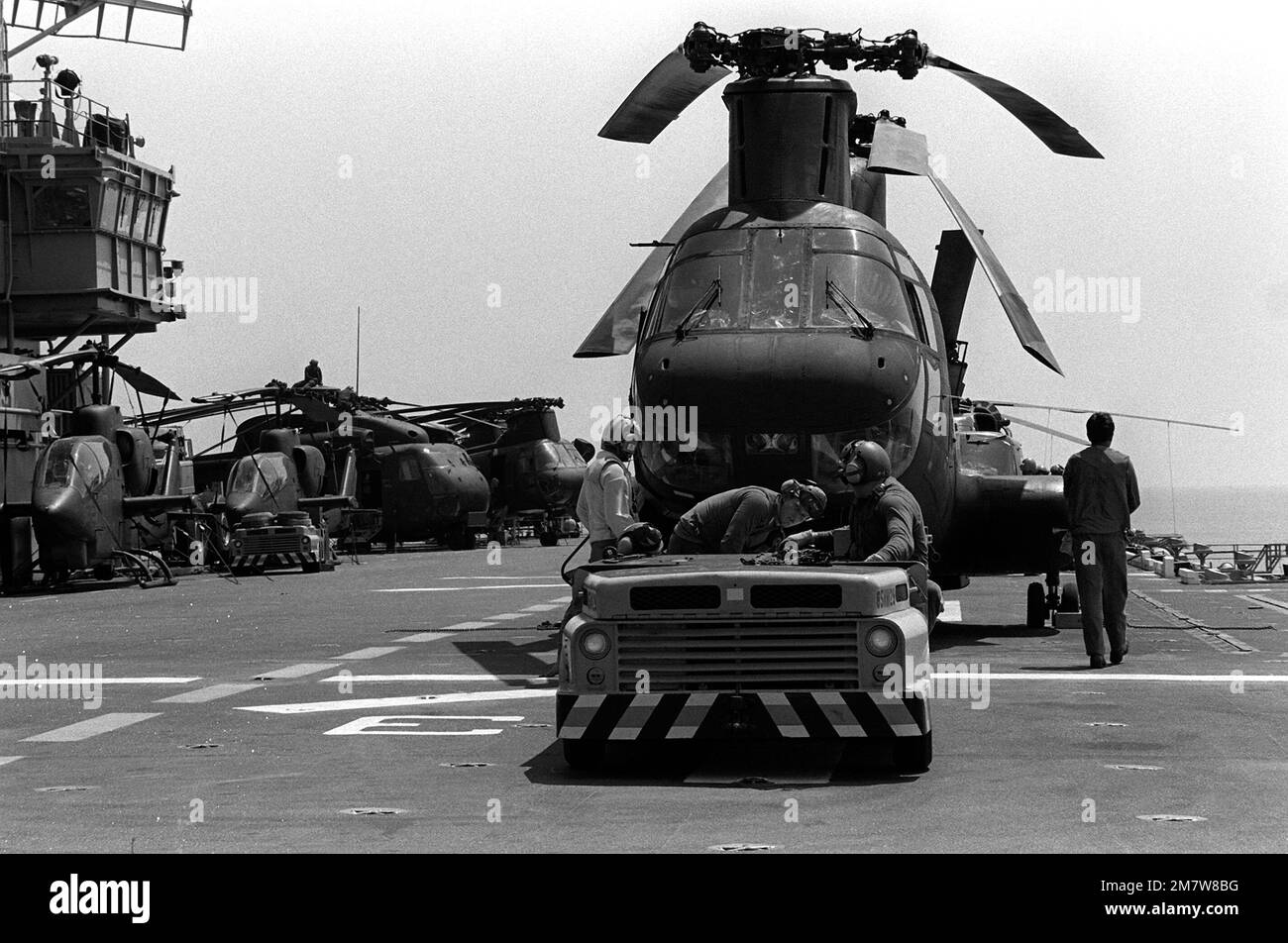 A tow tractor prepares to move a Marine CH-46 Sea Knight helicopter ...