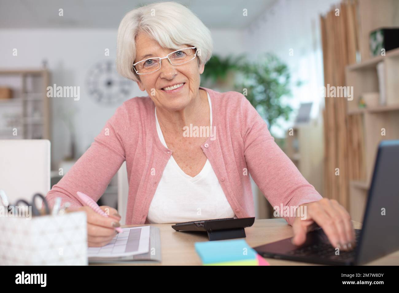 senior woman using laptop to complete paperwork Stock Photo - Alamy