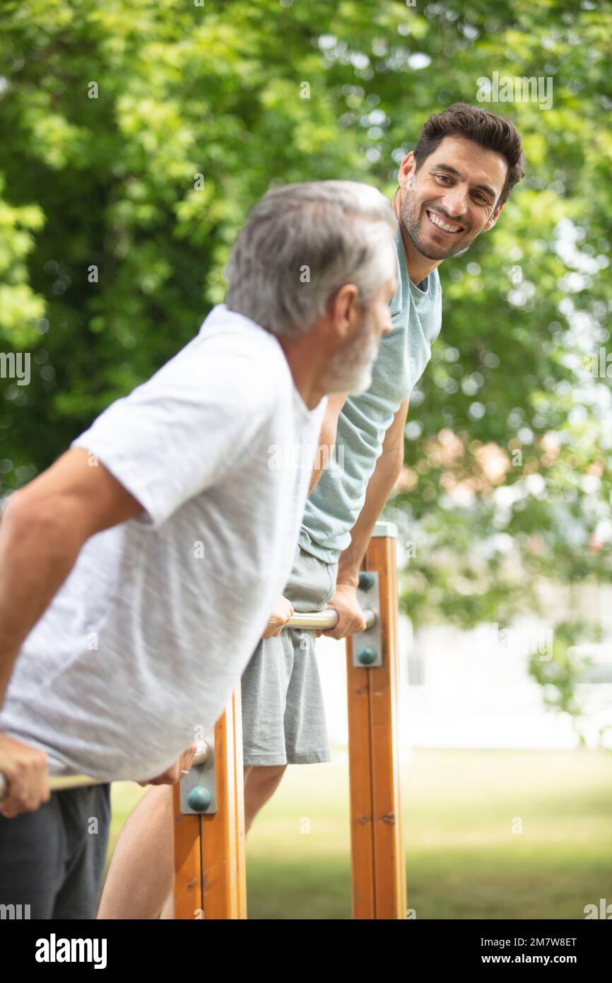 strong young man doing chin-up repetitions with his friends Stock Photo ...