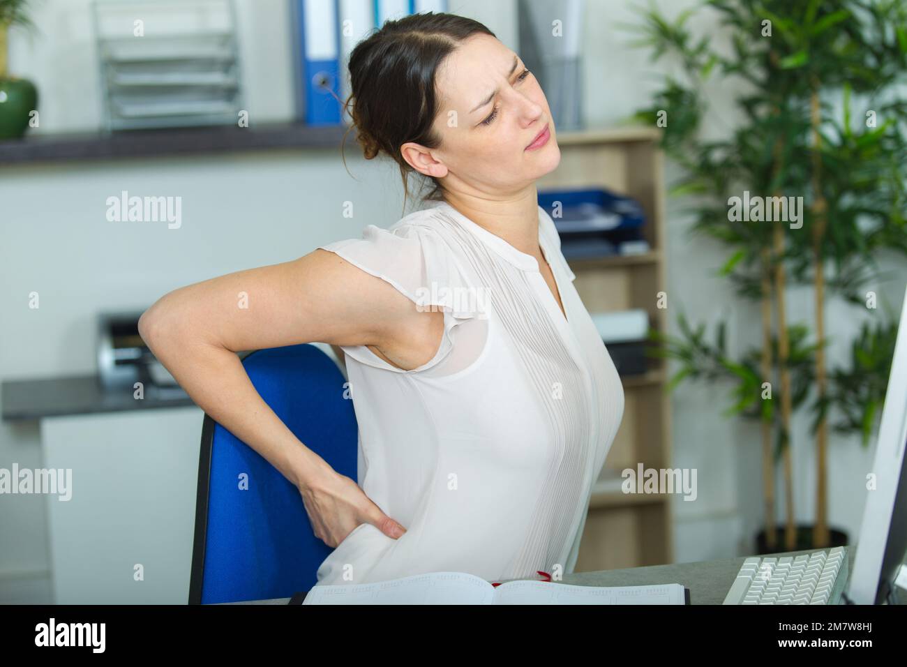 woman having back pain in office Stock Photo - Alamy